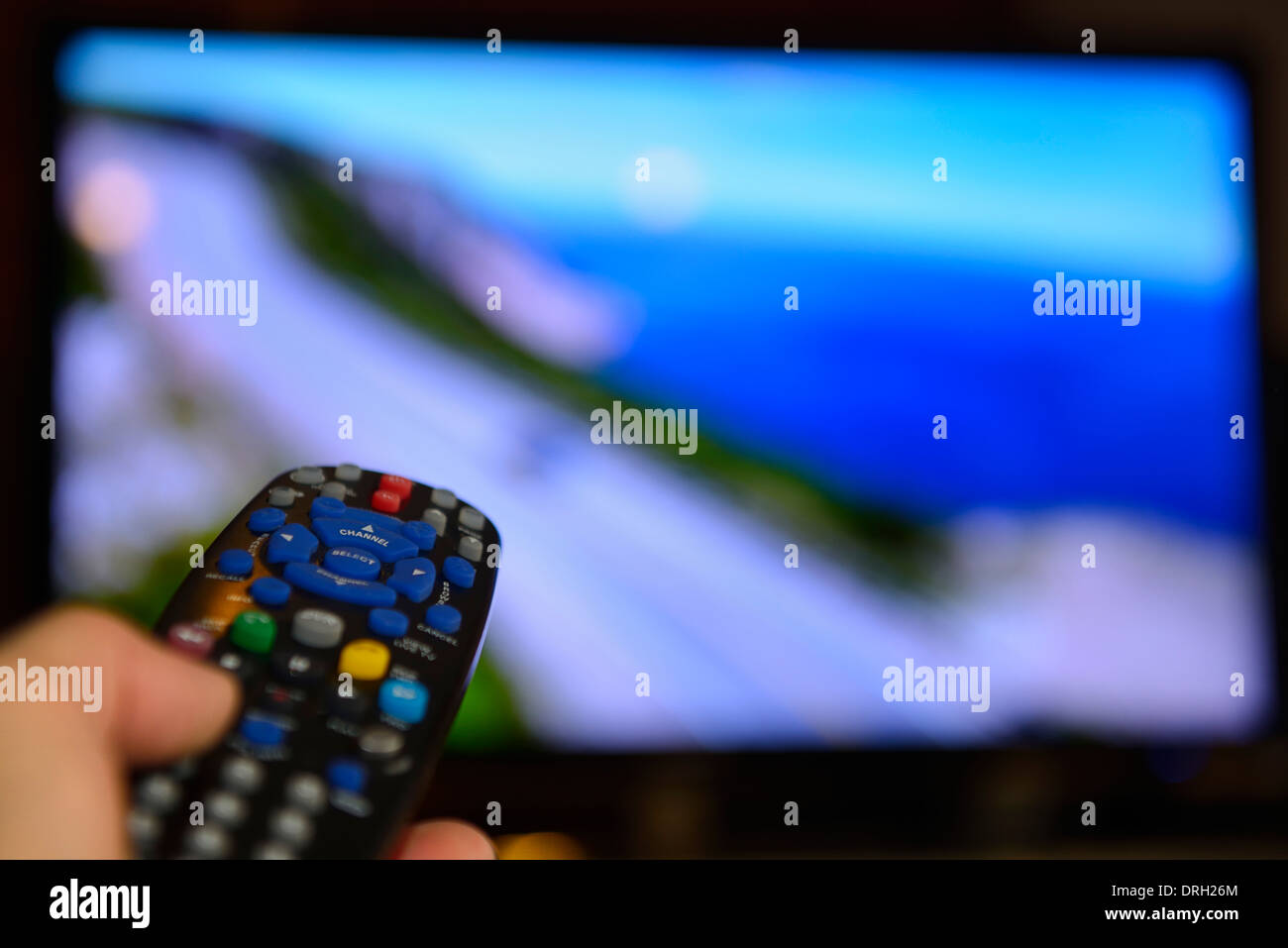 Person pointing the remote control towards a television screen at home ...