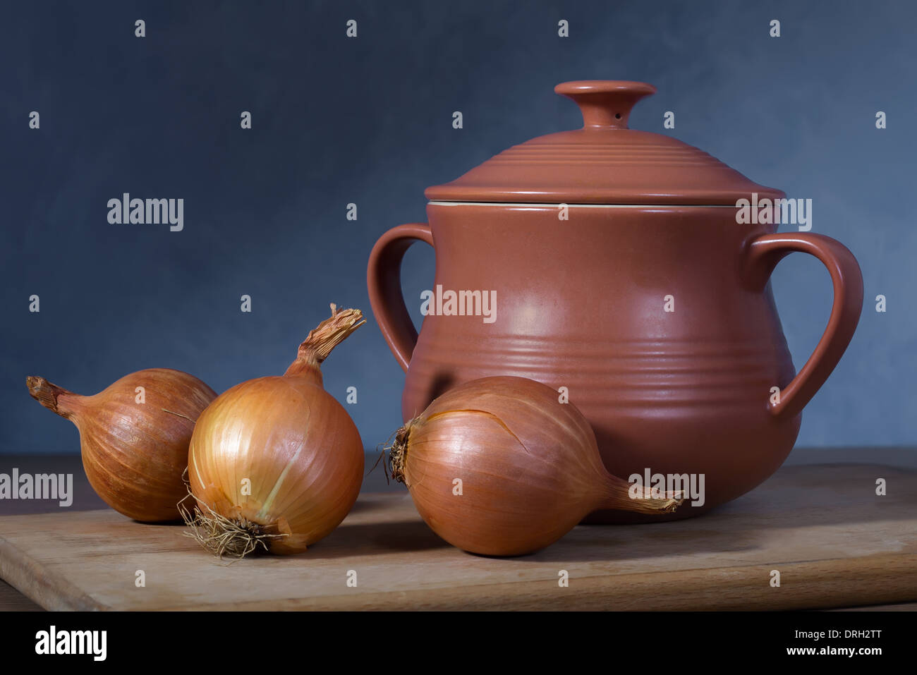 Still-life with a clay pot and onions on a wooden board Stock Photo - Alamy