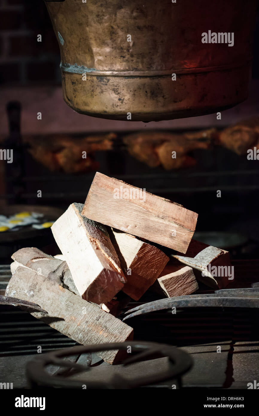 Closeup of old hearth bonfire with pile of fire wood and pot. Indoor ...