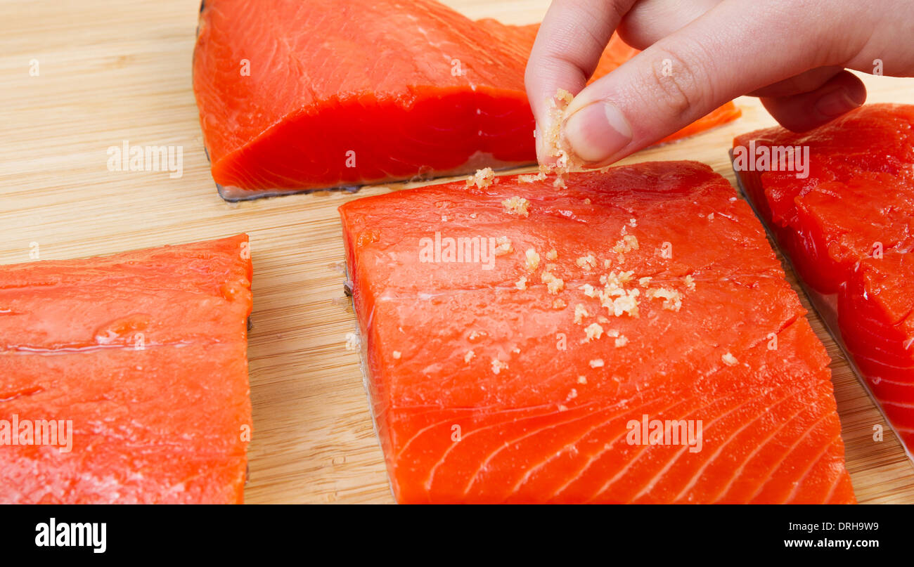 Horizontal photo of female fingers placing sea salt on fresh pieces of ...