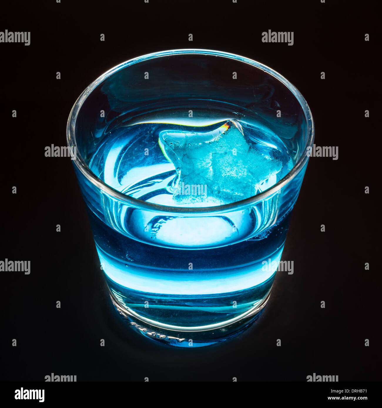 A star-shaped ice cube in a glass of water. Dark background, not ...