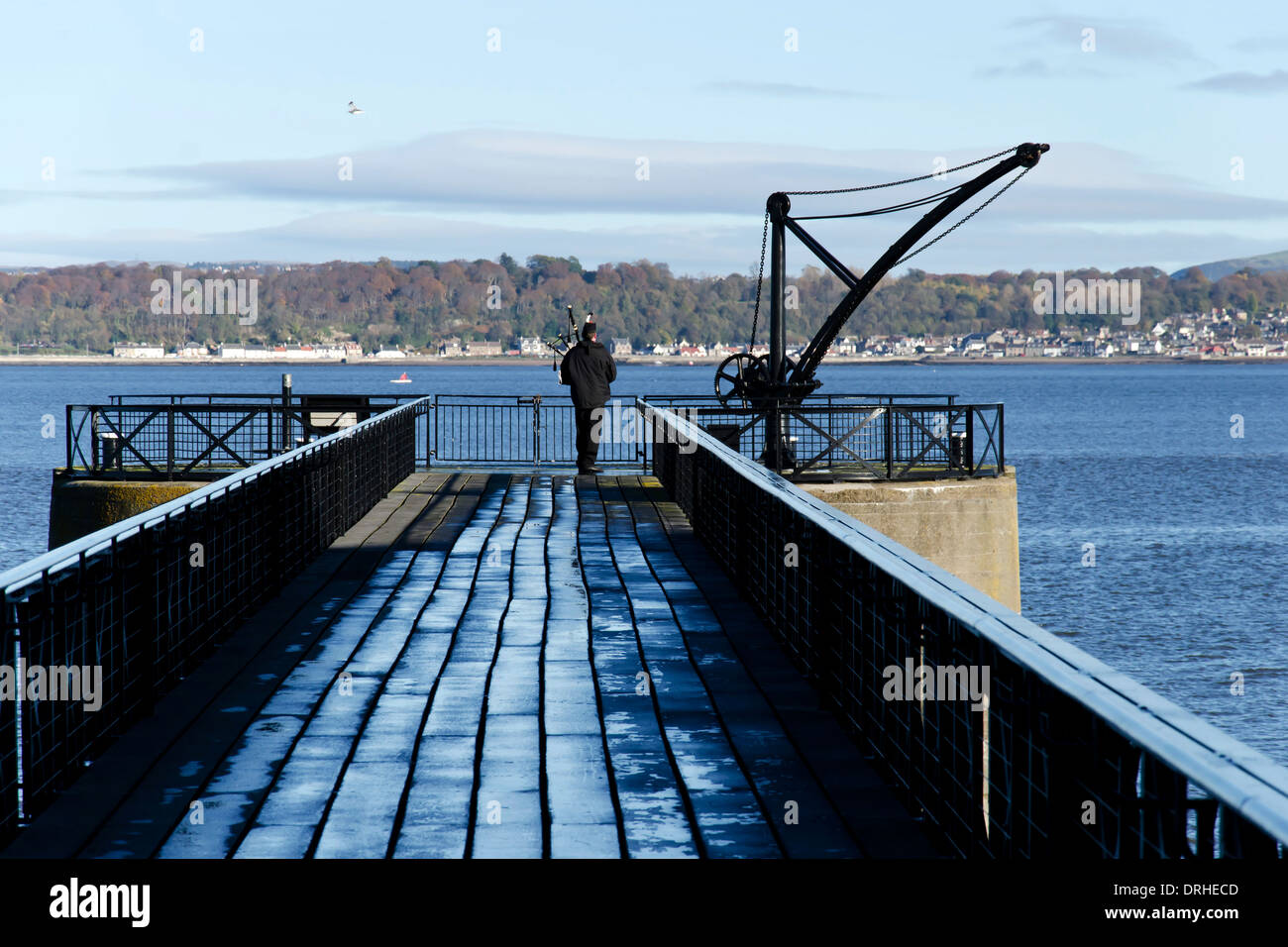 Piper playing at the end of the pier at Blackness Castle on the shore ...