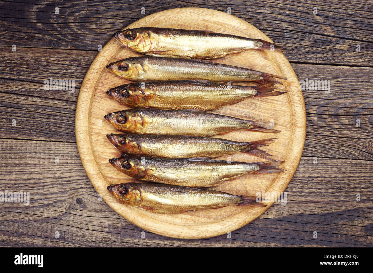 Smoked fish on a round cutting board on wooden table. Top view Stock ...