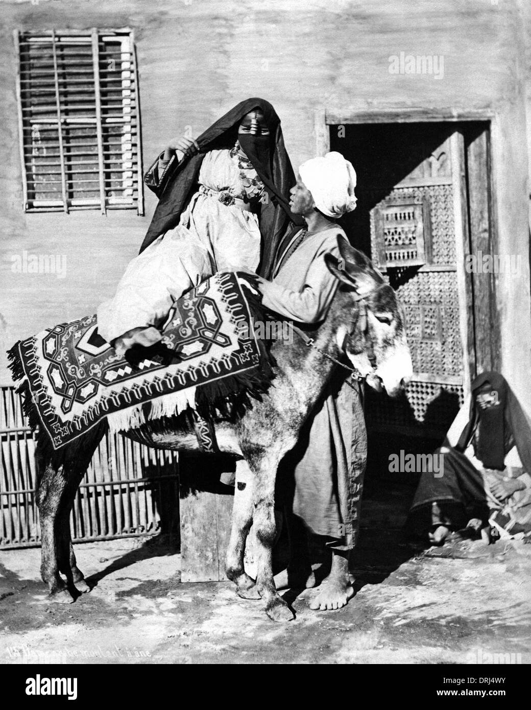 Veiled woman mounting donkey, Egypt Stock Photo - Alamy