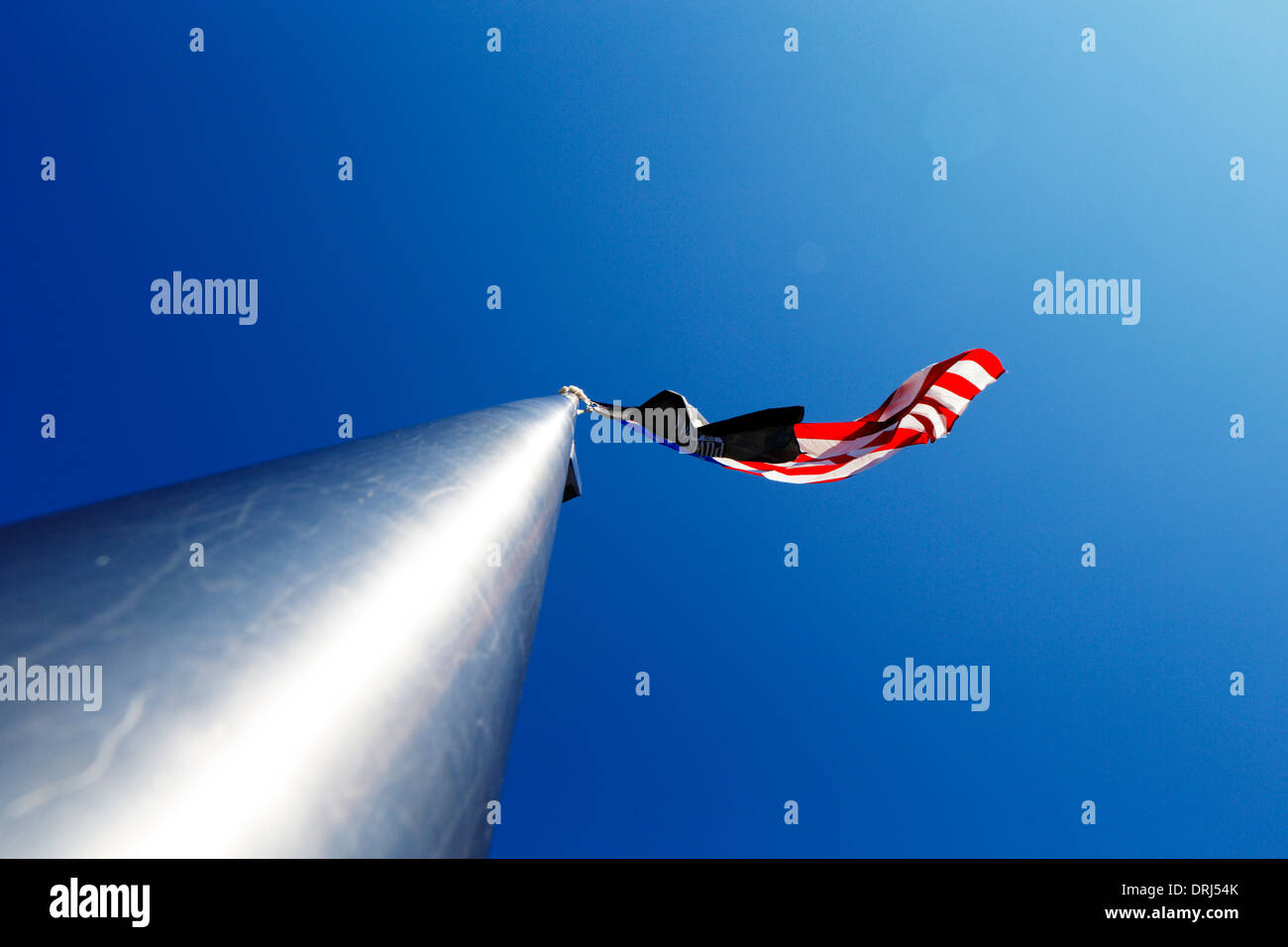American flag on a metal pole floating over a blue sky Stock Photo - Alamy