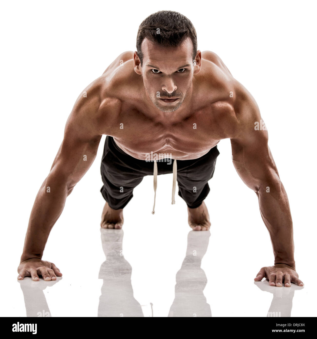 Muscle man making push ups in studio, isolated over a white background ...