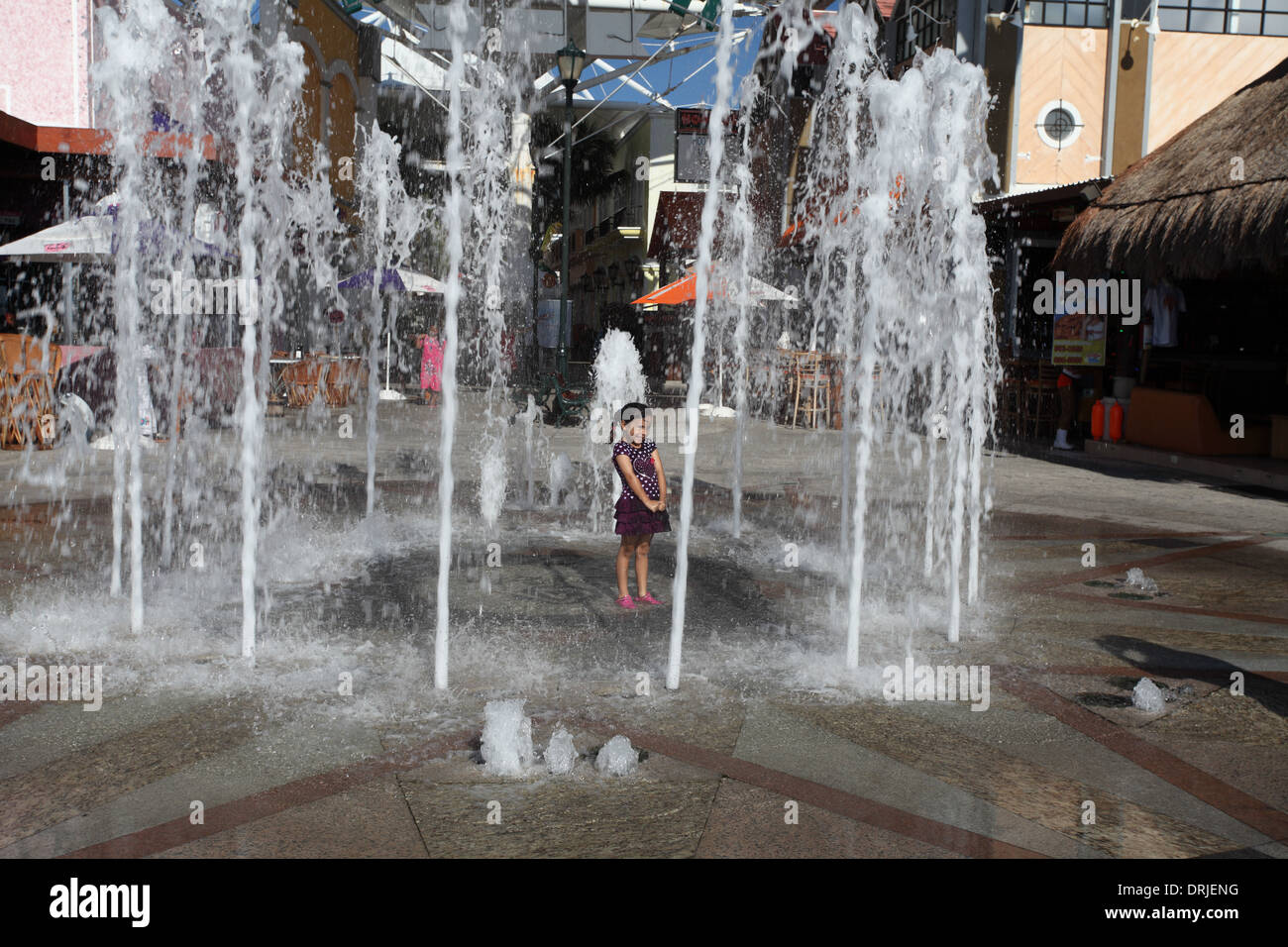 Little Mexican girl cooling in the center of a water fountain in La ...