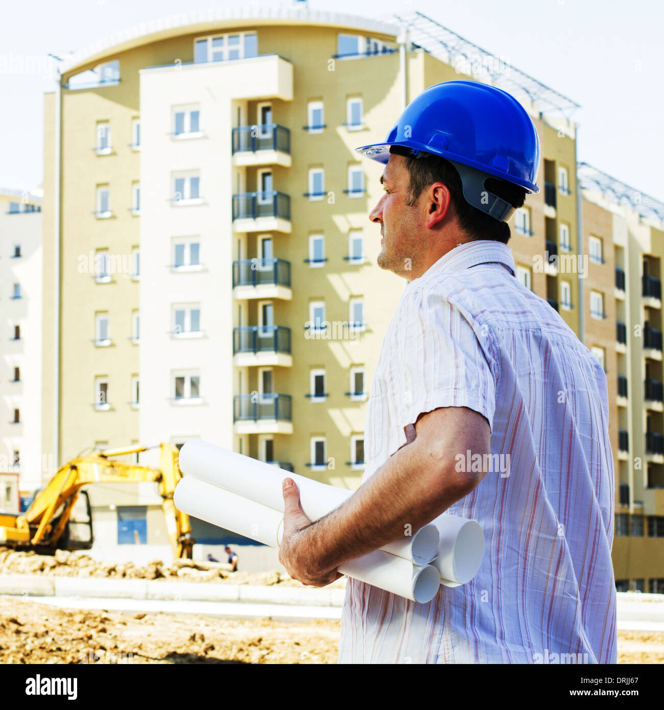 Engineer with blue hard hat holds blueprint on the construction site ...