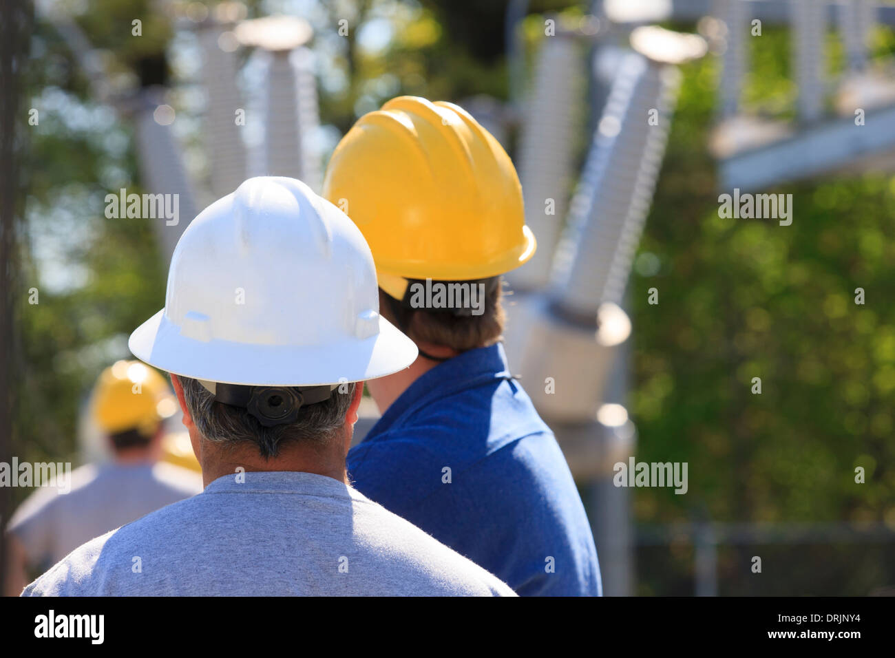 Power engineers looking at high voltage power distribution station ...
