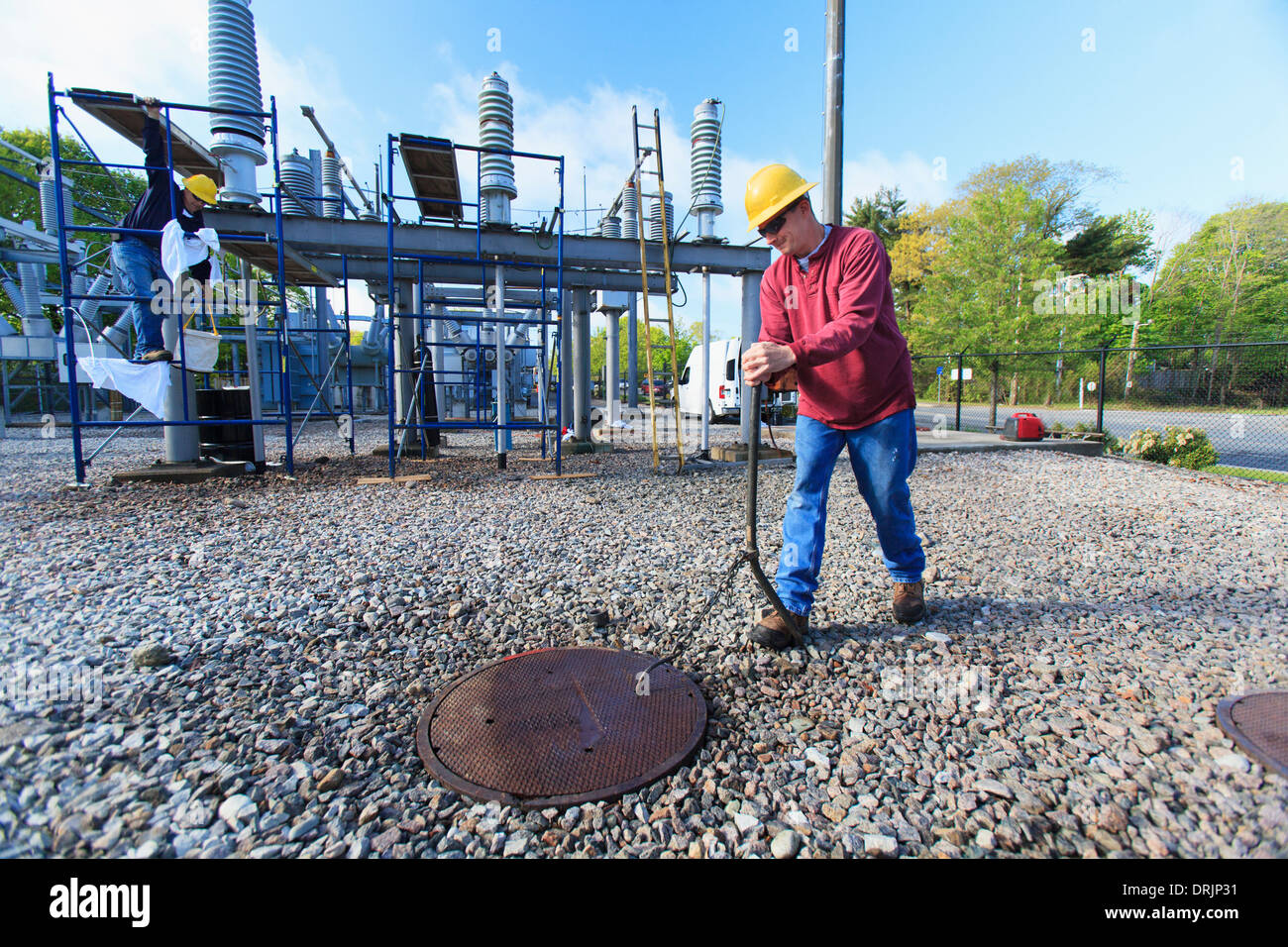 Power engineer accessing manhole cover at high voltage power ...