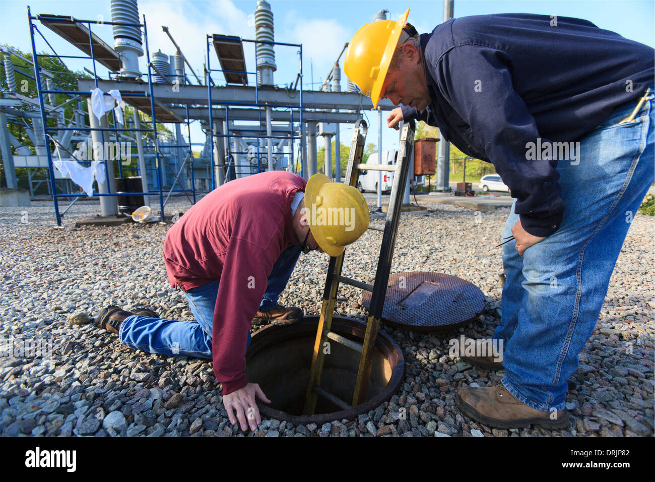 Power engineers placing ladder inside manhole at high voltage power ...