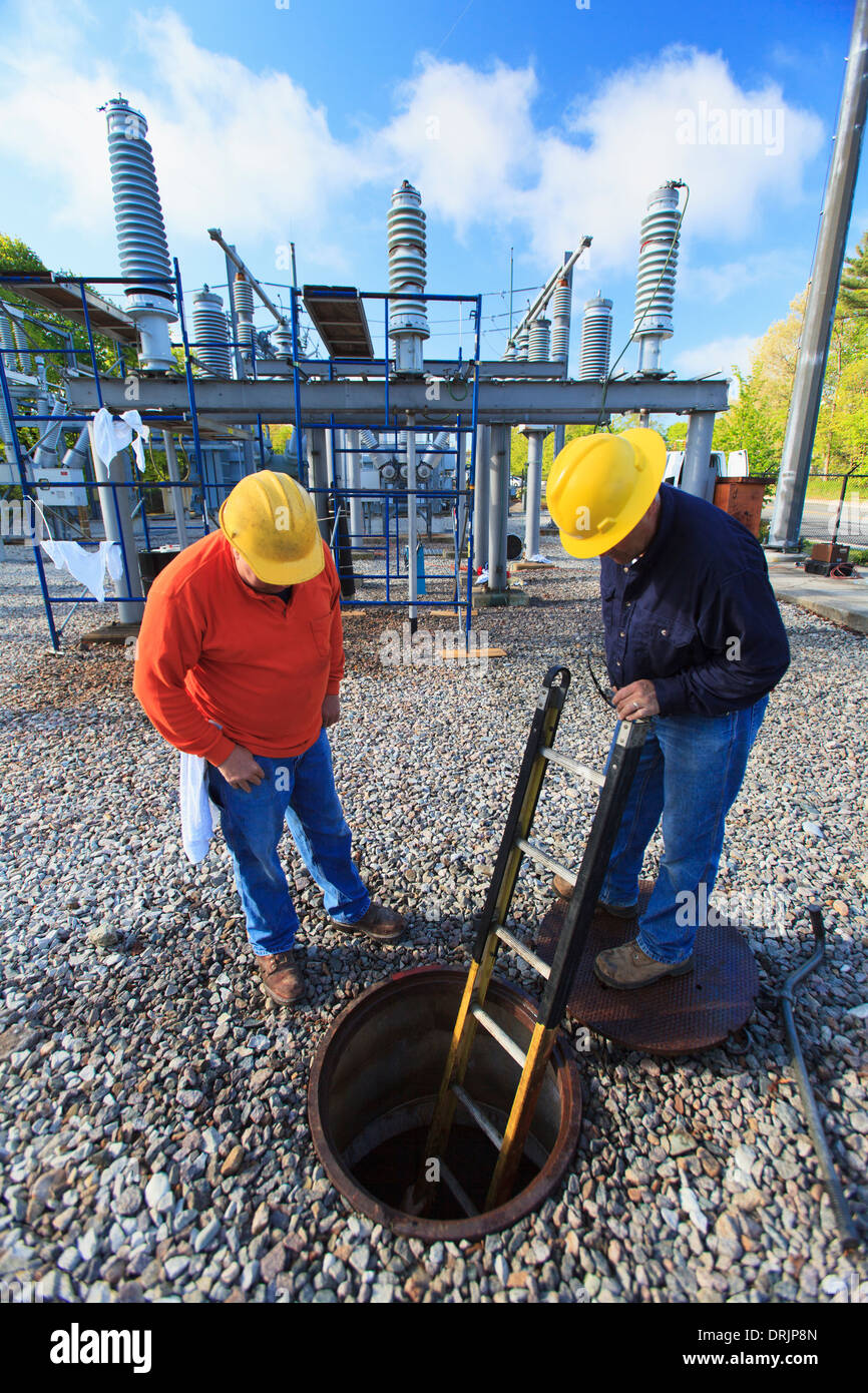 Power engineers looking inside manhole at high voltage power ...