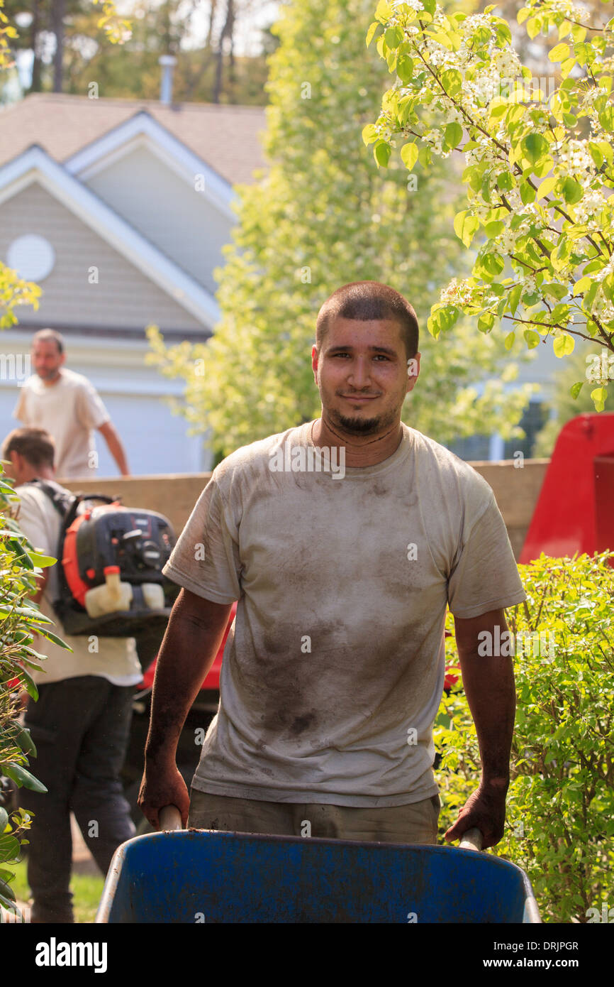 Landscaper carrying mulch to a garden in wheelbarrow Stock Photo - Alamy