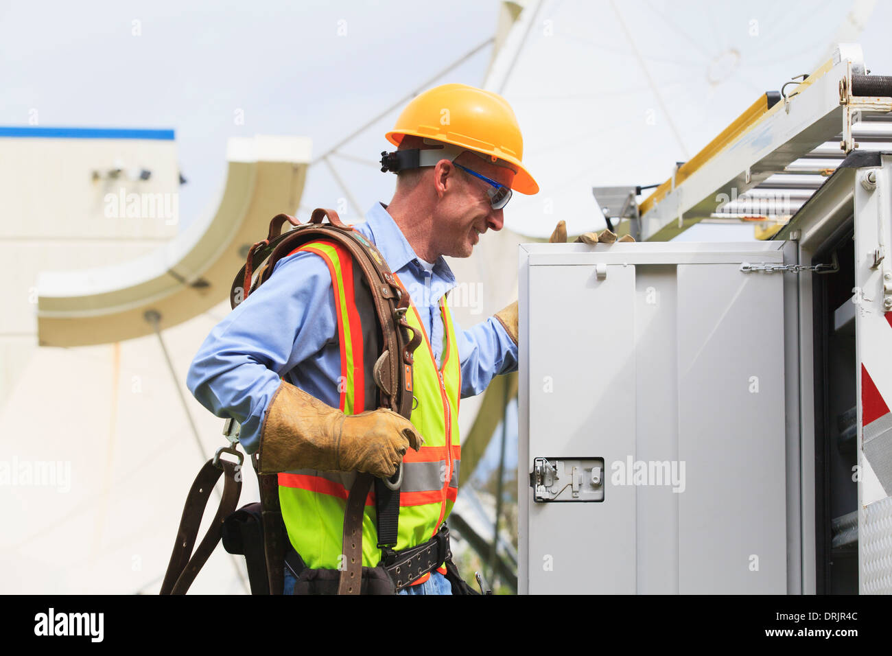 Communications engineer getting equipment from truck with satellite ...
