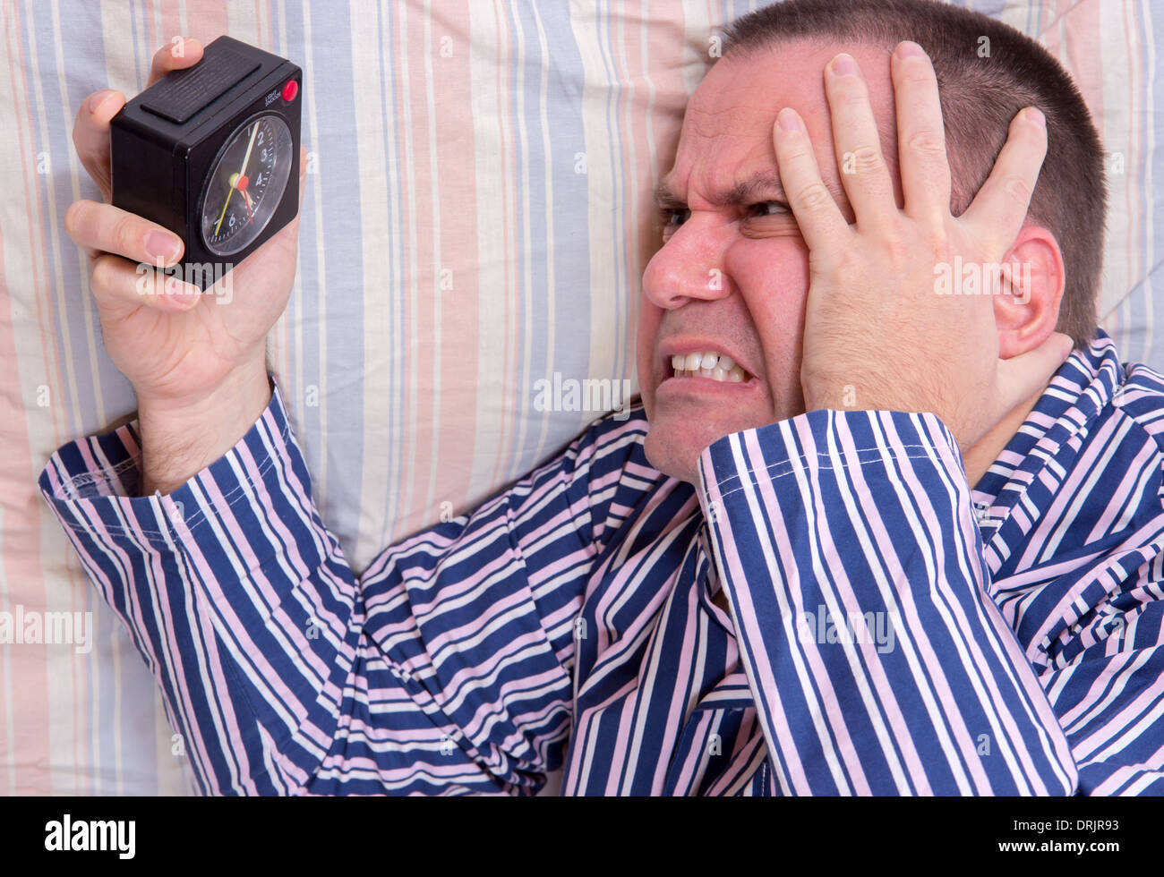 man in bed watching alarm clock Stock Photo - Alamy
