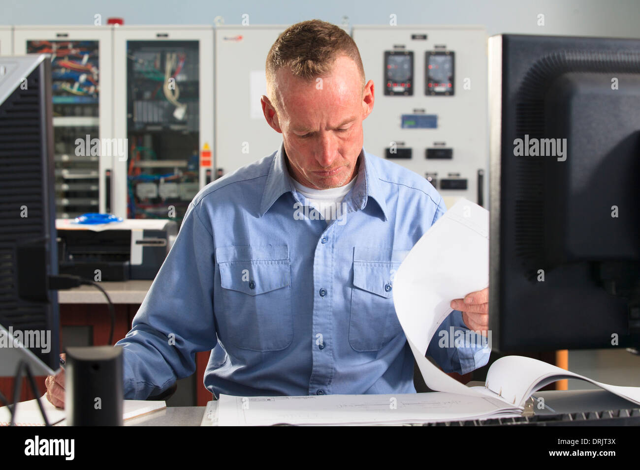 Electrical engineer reviewing logs in central operations room of power ...
