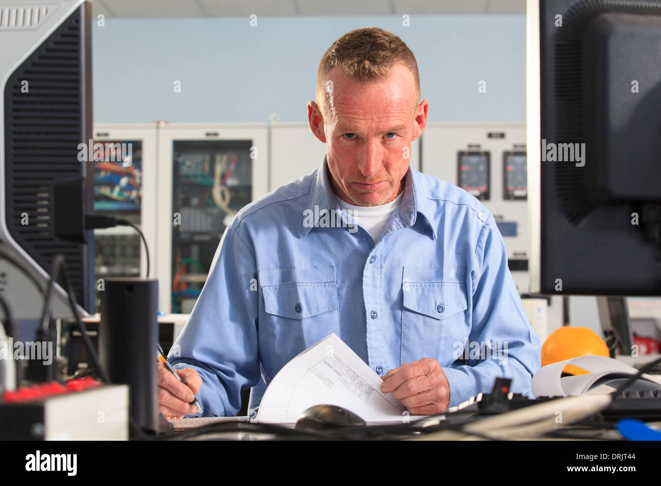 Electrical engineer reviewing process flow diagrams in central ...