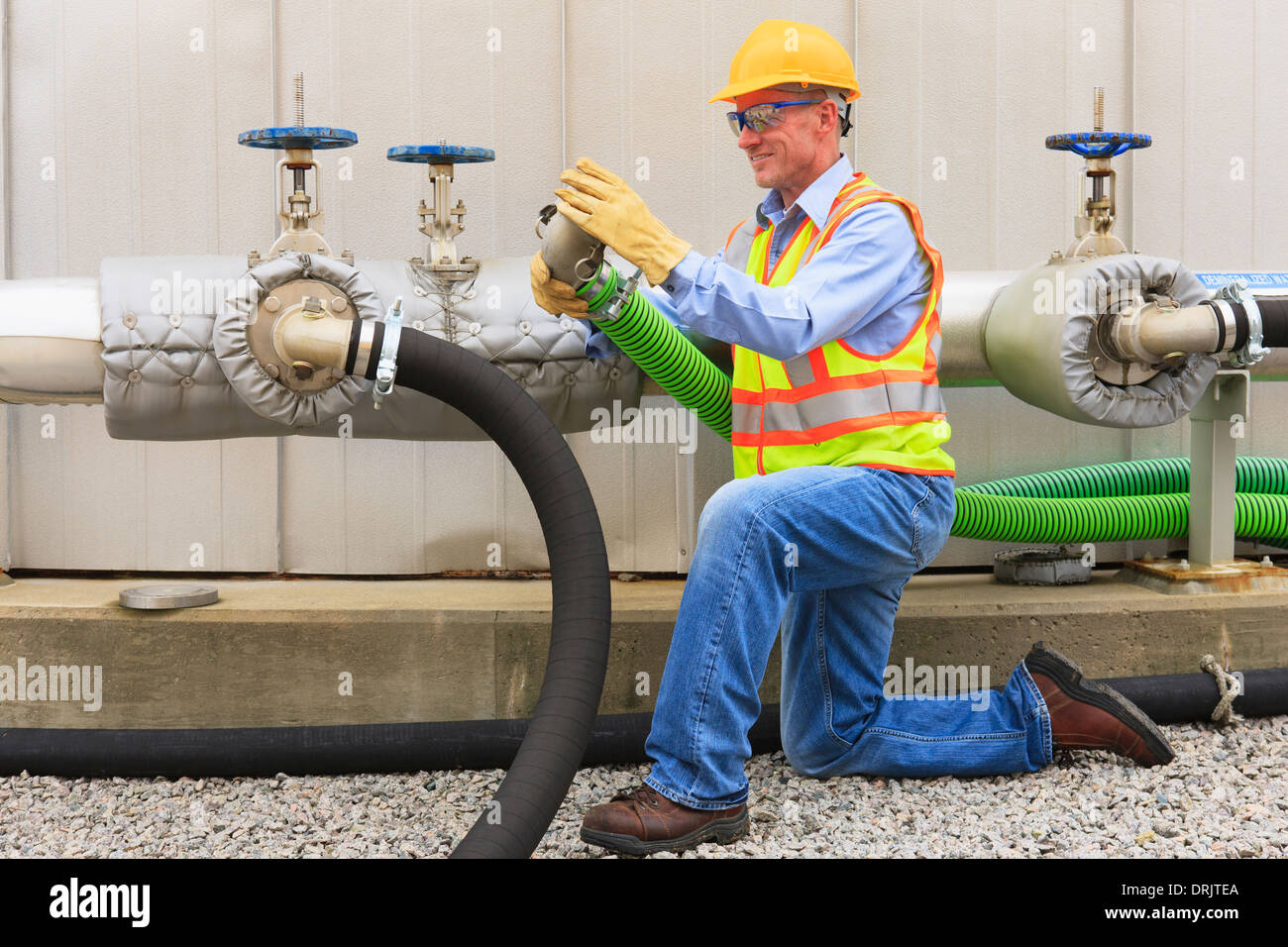 Engineer at electric power plant examining connection hose near water ...