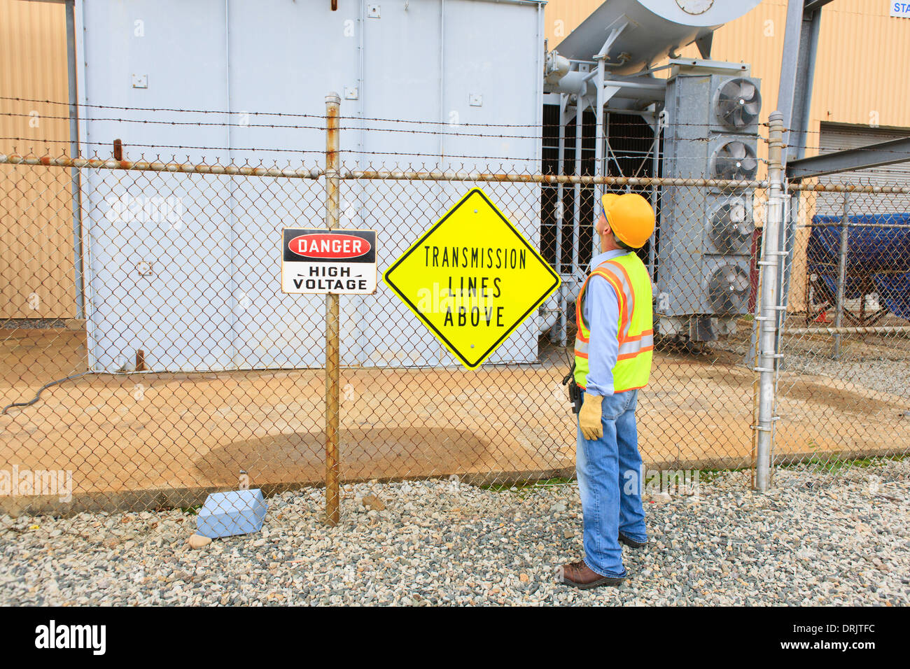 Engineer at electric power plant looking at transmission lines at ...