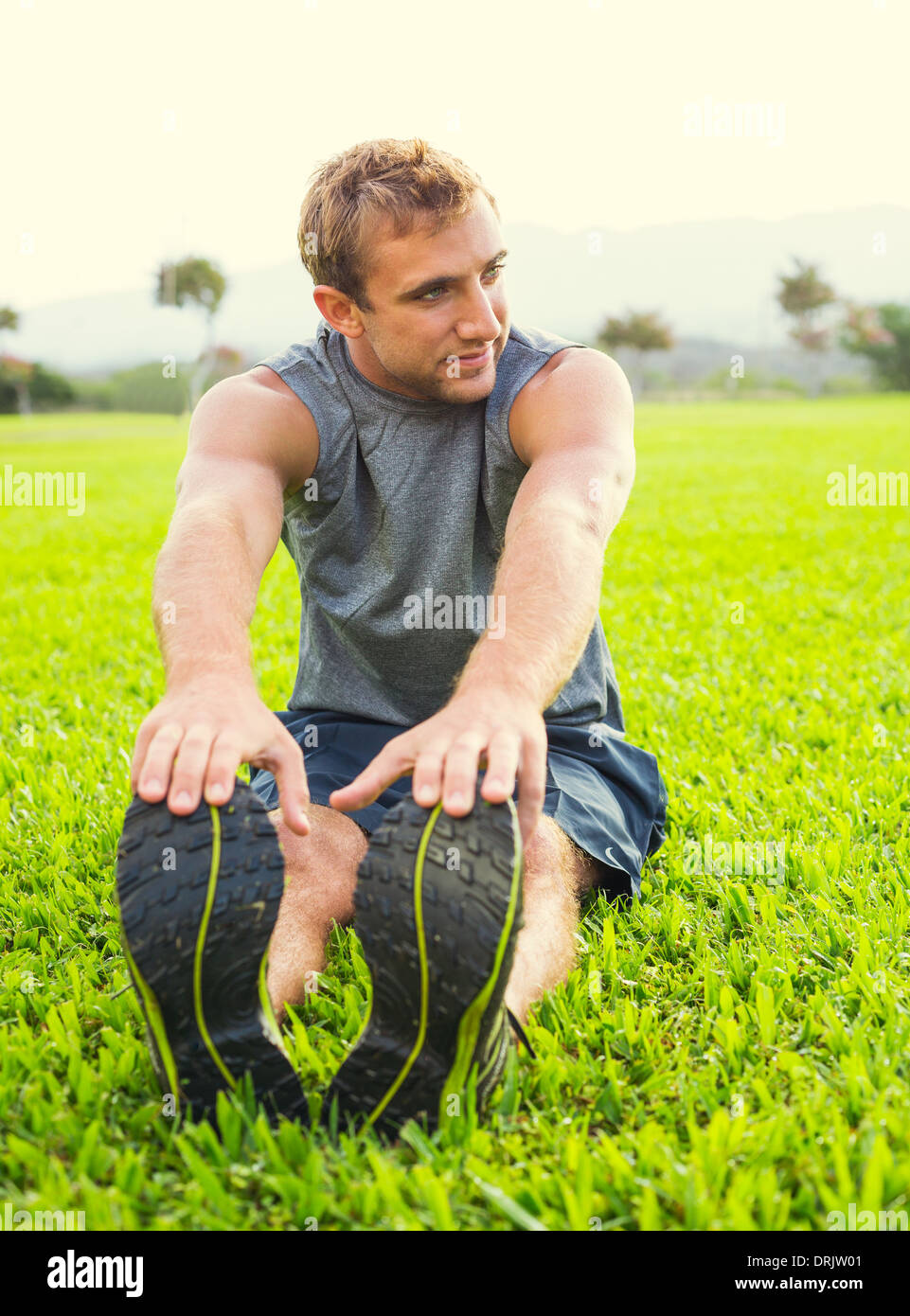 Attractive fit young man stretching before exercise, sunrise early ...