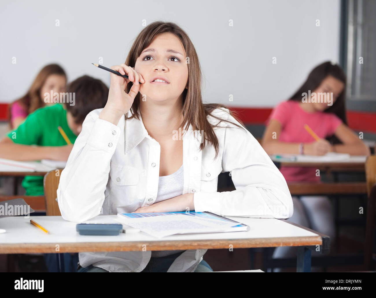 Thoughtful Female Student Looking Up At Desk Stock Photo - Alamy