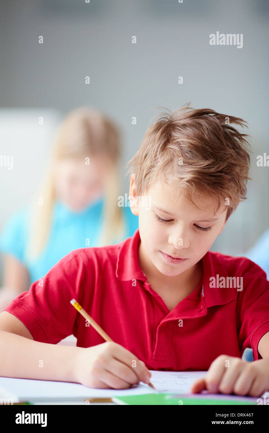Portrait of cute schoolboy drawing at workplace during lesson Stock ...