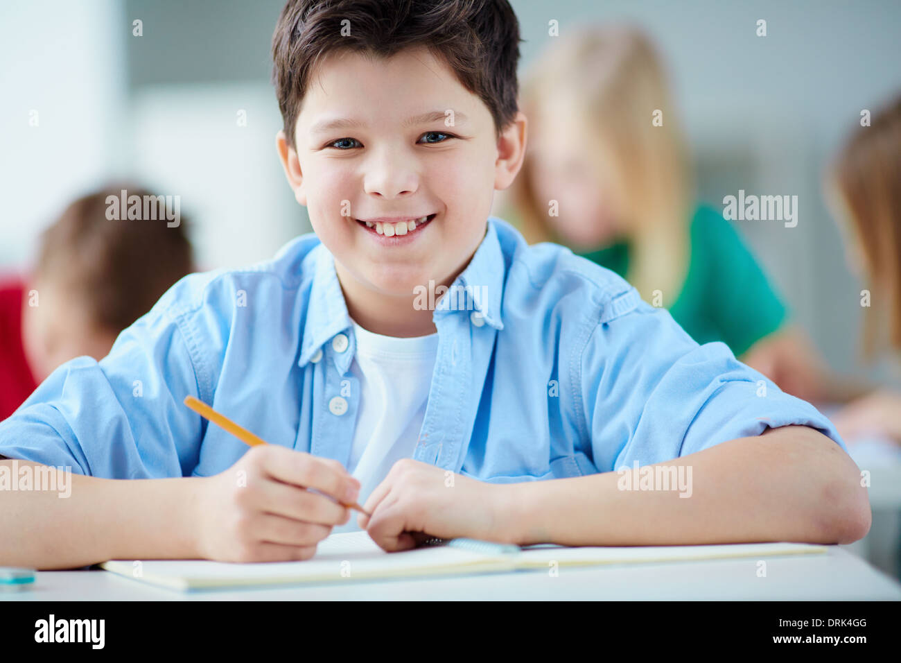 Portrait of happy schoolboy at workplace looking at camera with his ...