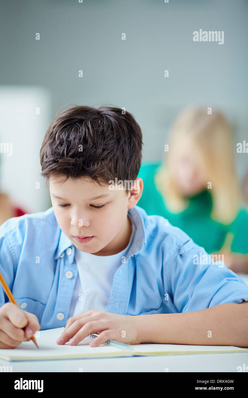 Portrait of cute schoolboy drawing at workplace during lesson Stock ...