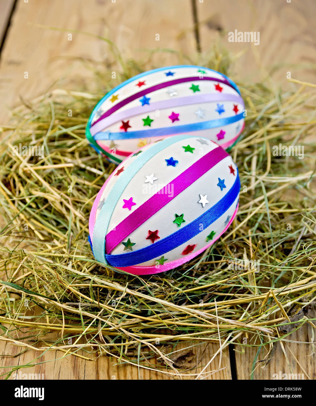 Two easter eggs, decorated with multicolored braid and sparkles as ...