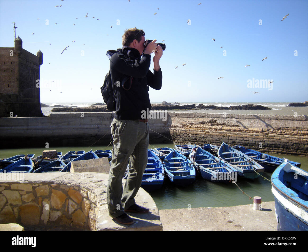 A photographer works on the harbour by traditional fishing boats as ...