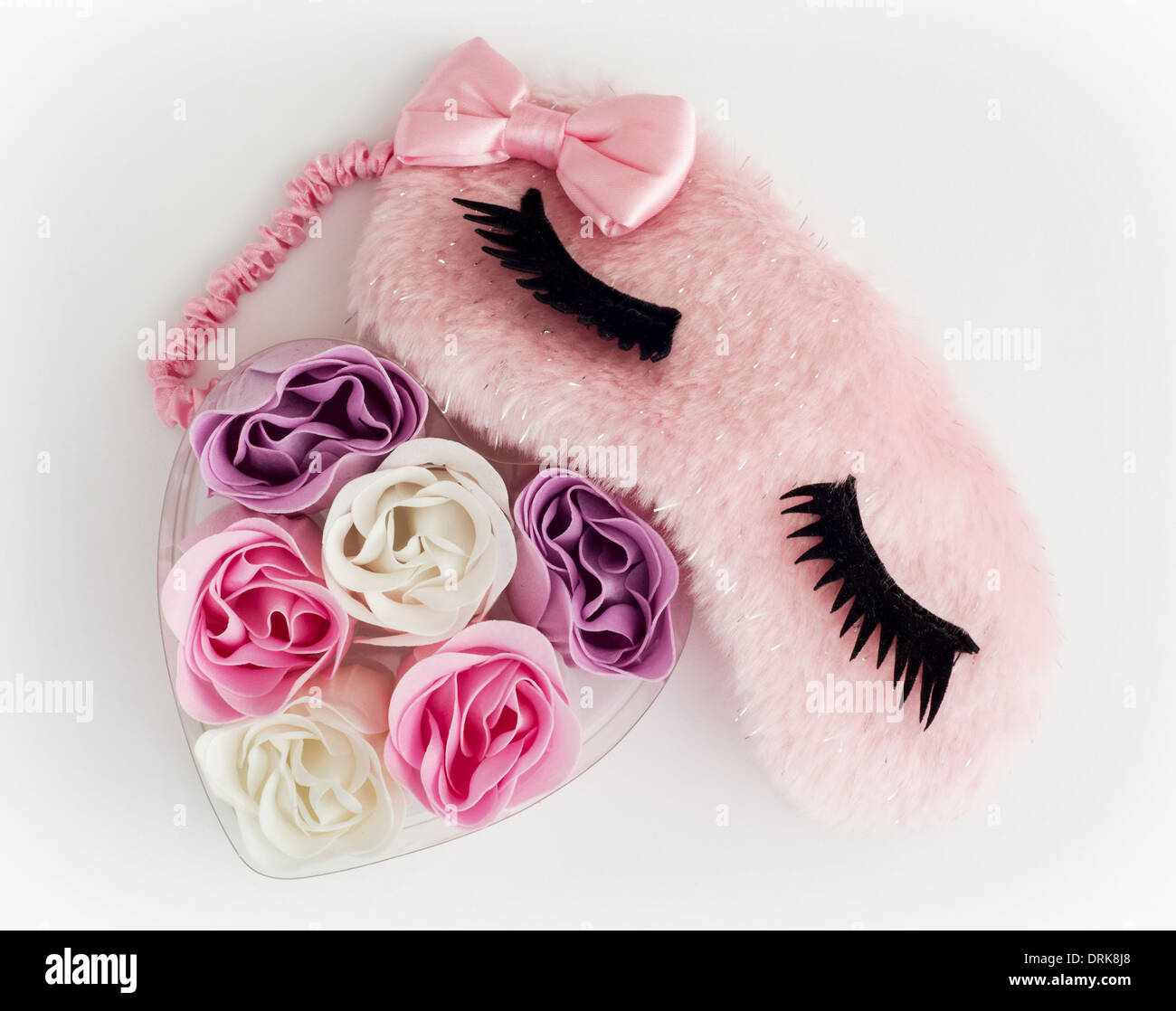 Pink sleeping mask and little heart made of fabric flowers on a white ...