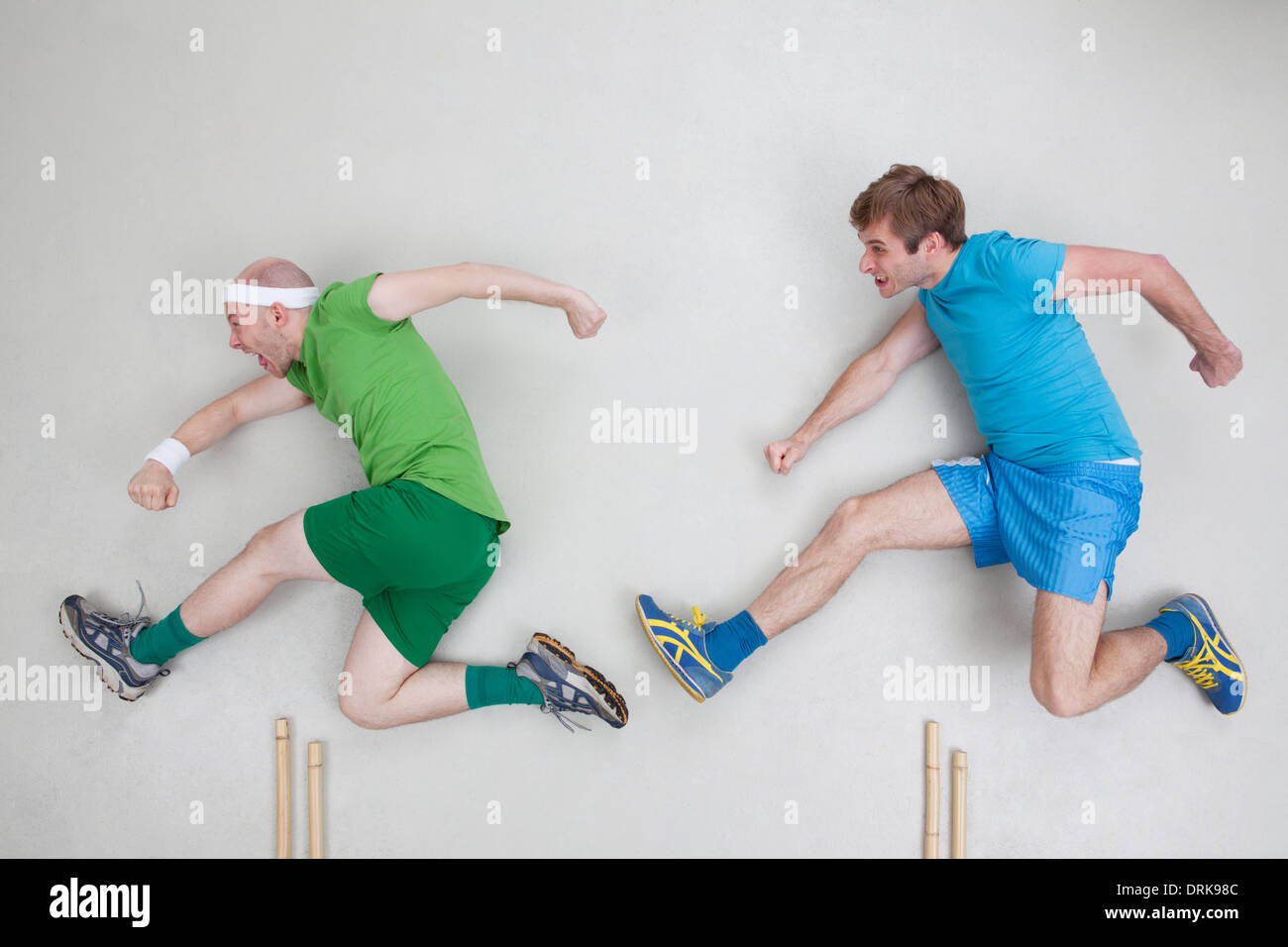 Two men jumping over hurdles Stock Photo - Alamy