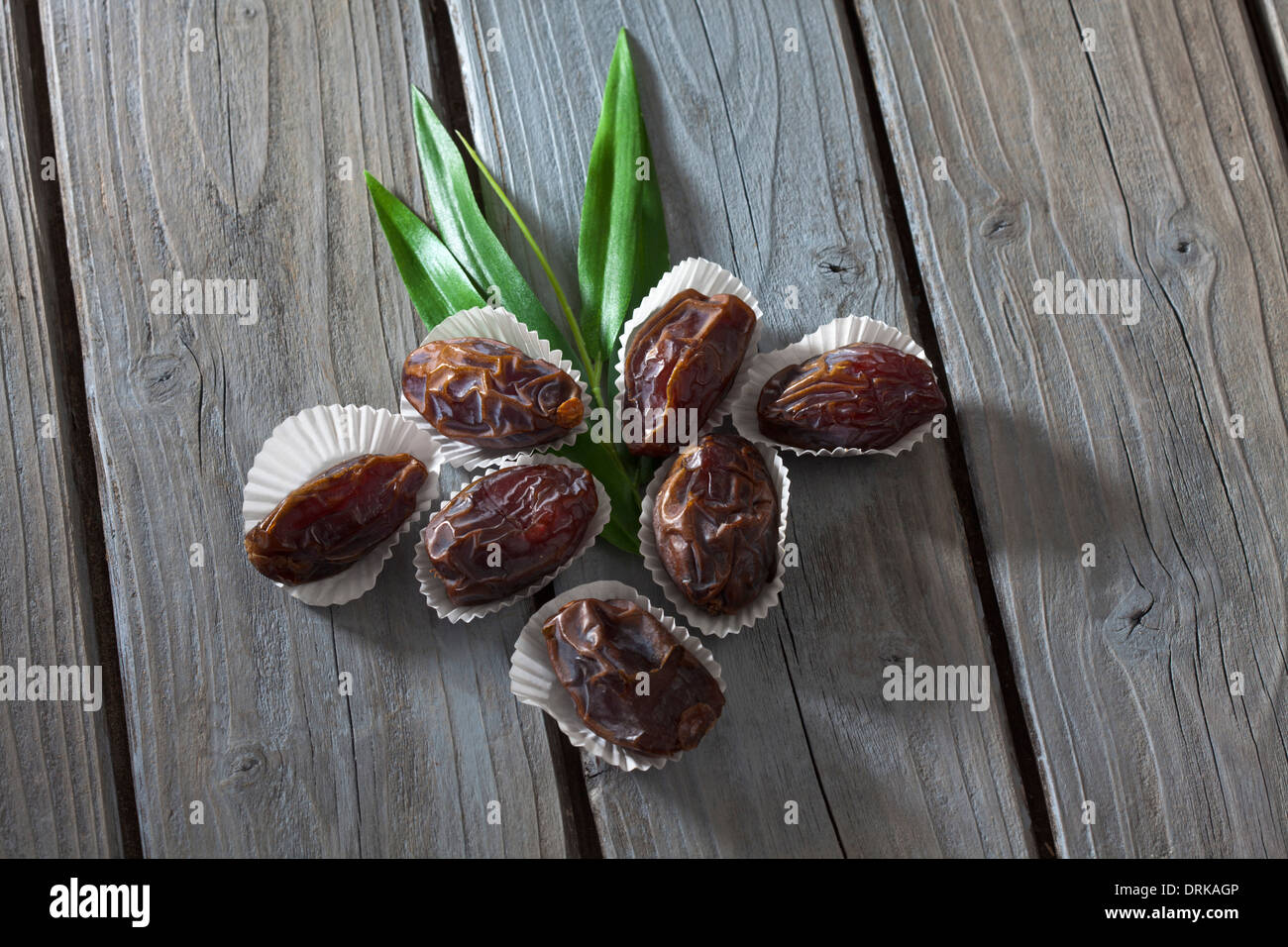 Seven dates in paper cups on wooden table Stock Photo - Alamy