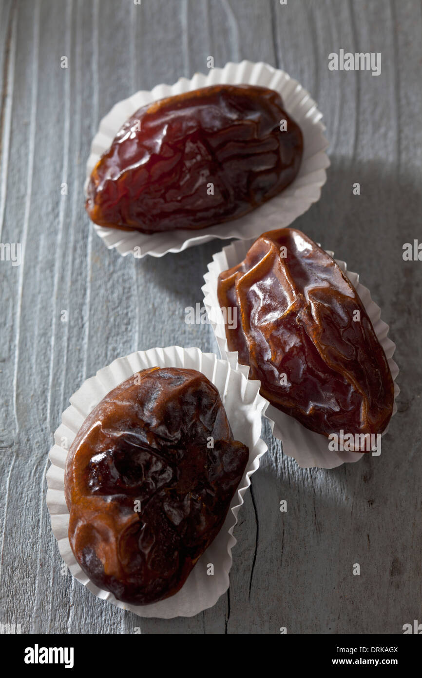 Three dates in paper cups on wooden table Stock Photo - Alamy
