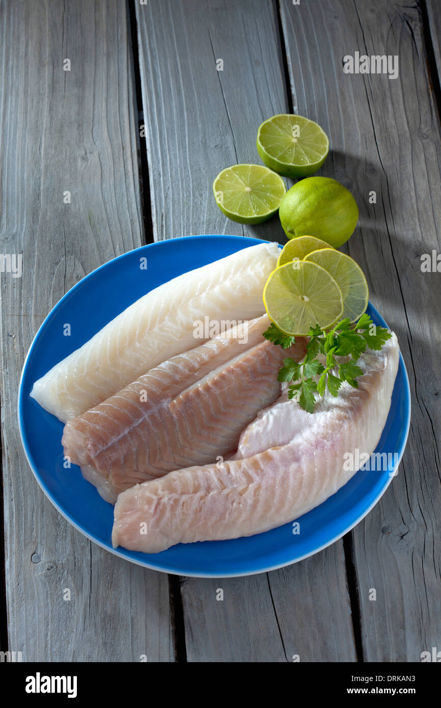 Fish fillets of codfish, coalfish and redfish with slices of limes on ...