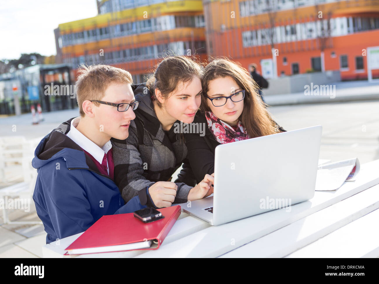 Three students using laptop outdoors Stock Photo - Alamy