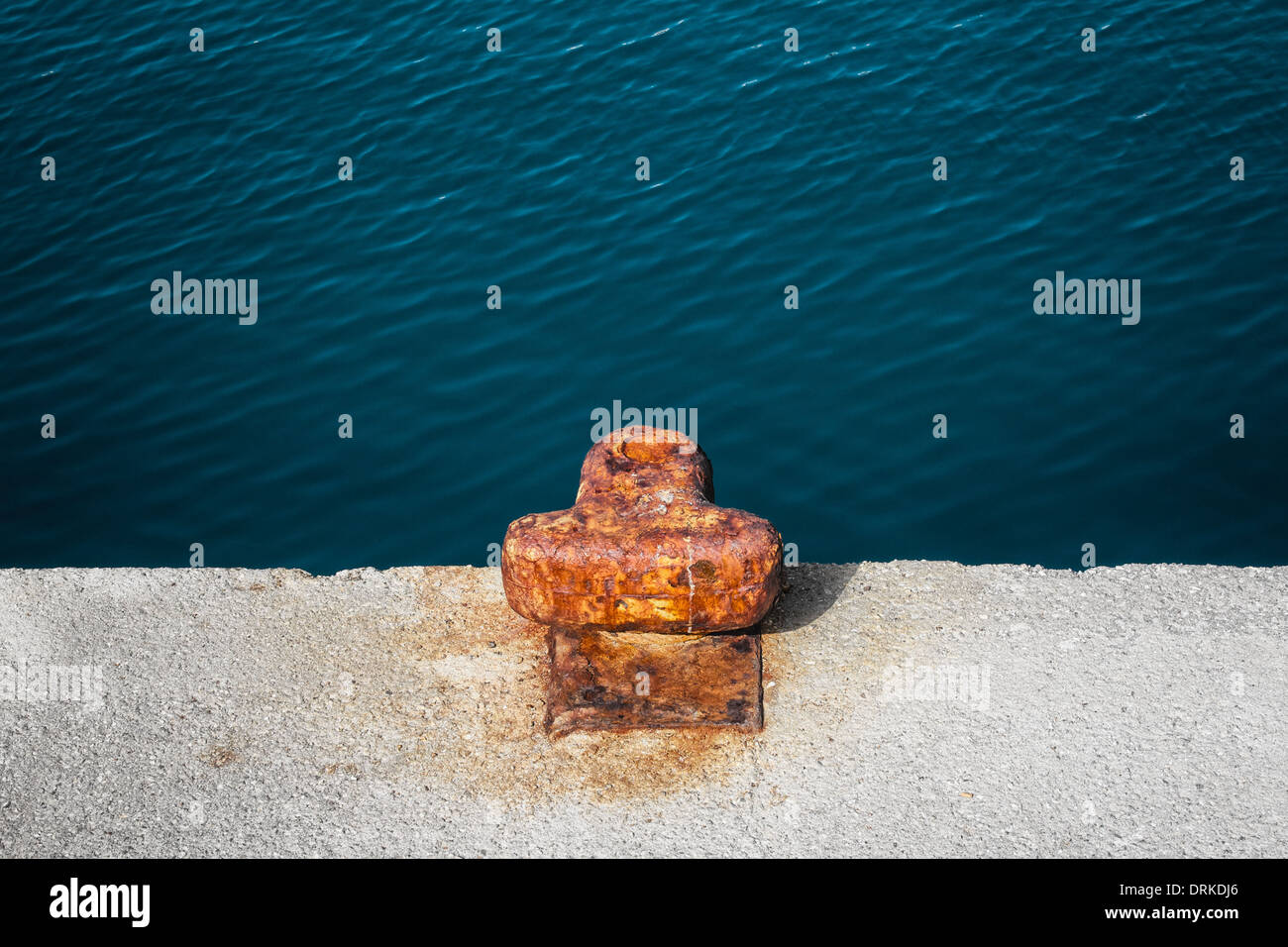 A semi-abstract image with a rust-encrusted bollard on a concrete quay ...