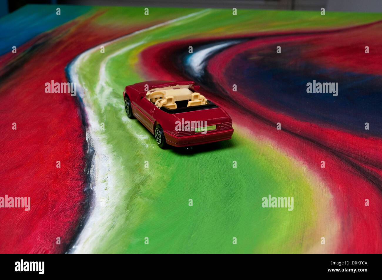 Convertible toy car driving across colourful landscape Stock Photo - Alamy