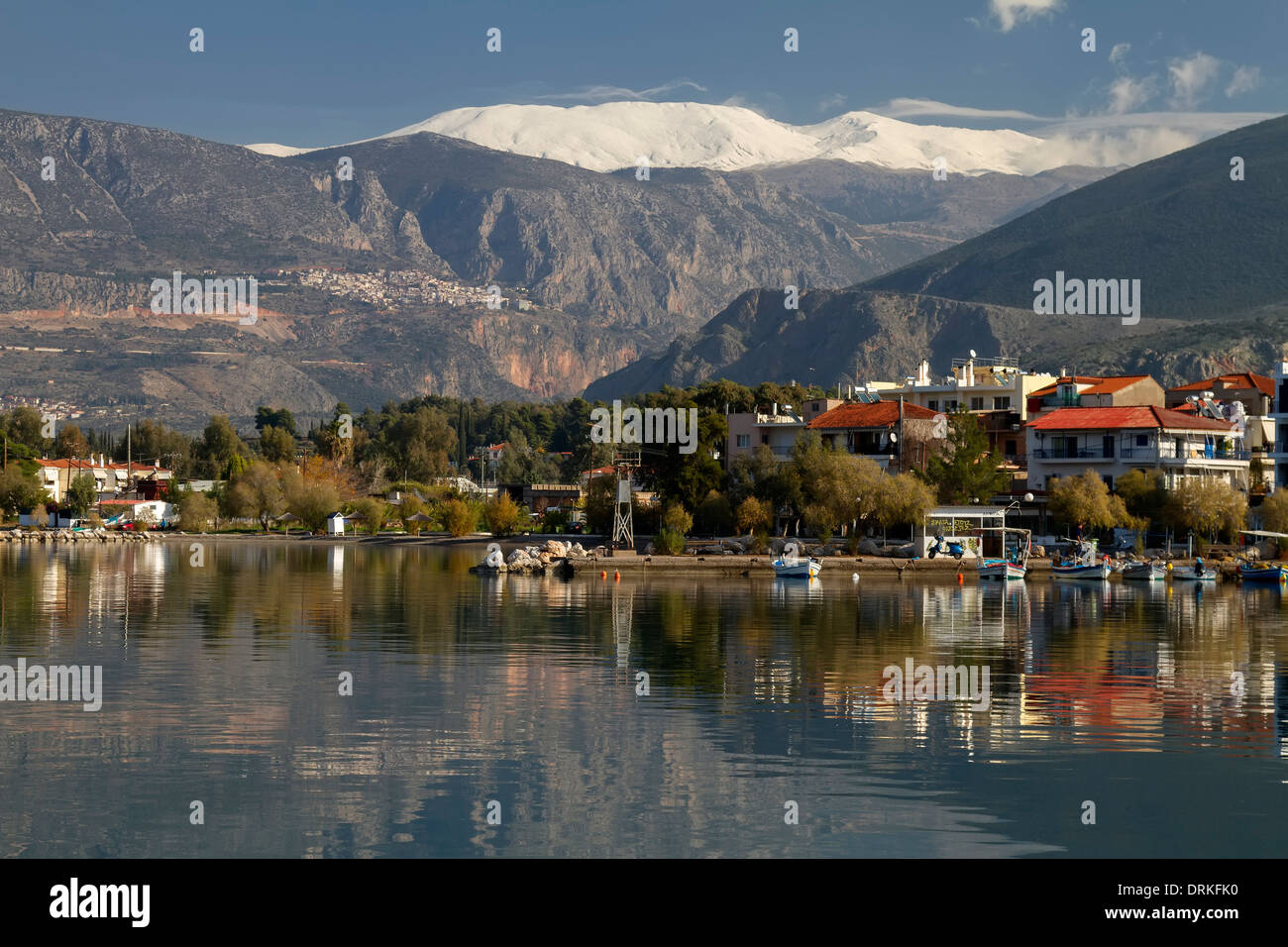 The town of Itea, Greece, the snow-capped mountain of Parnassos in the ...