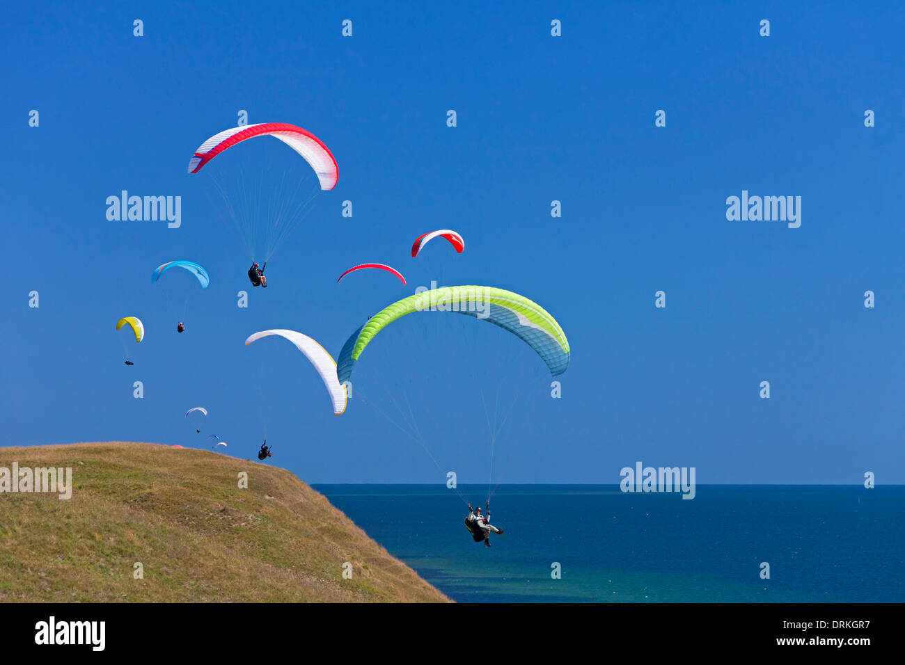 Group of paragliders in flight with colourful wings / canopies flying ...
