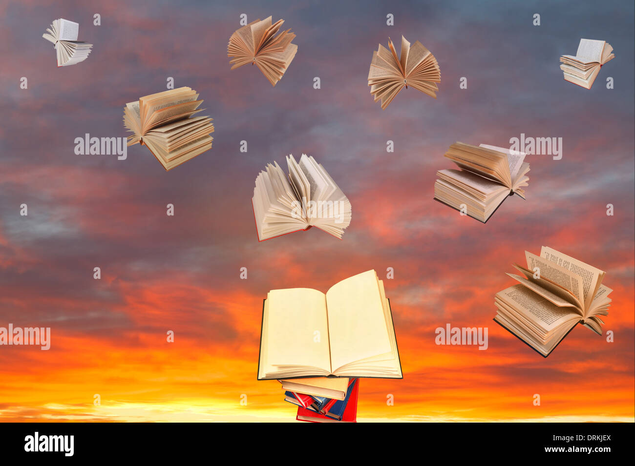 open book above of stack of books and sunset sky with flying books ...