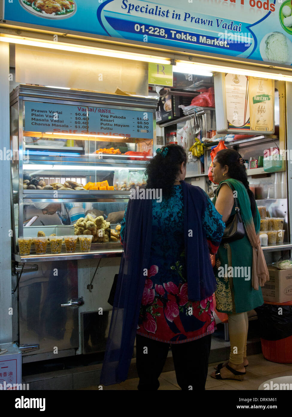 Two Indian women order food at a curry stall in a hawkers food plaza in ...