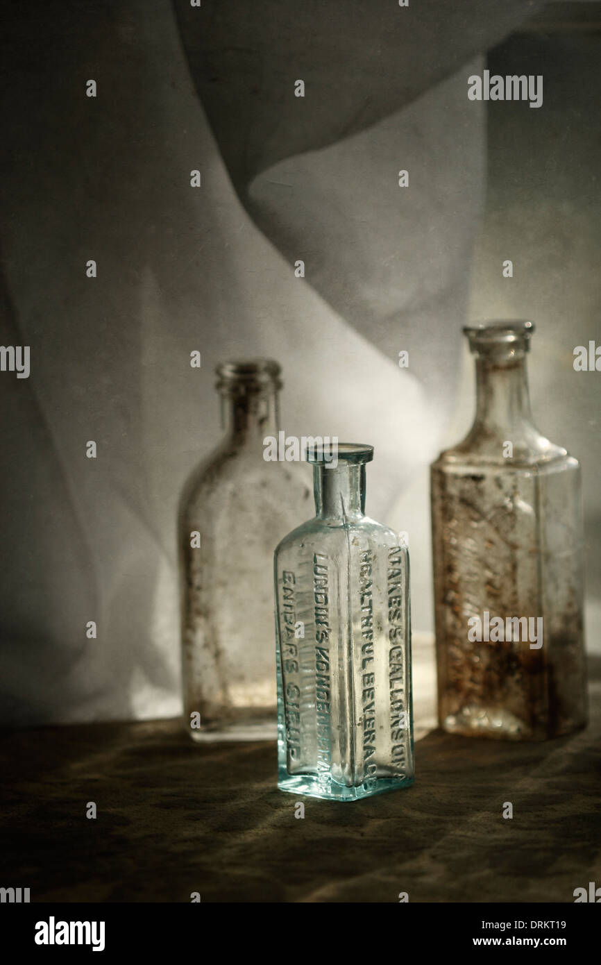 Three antique medicine bottles sit in front of a window Stock Photo - Alamy