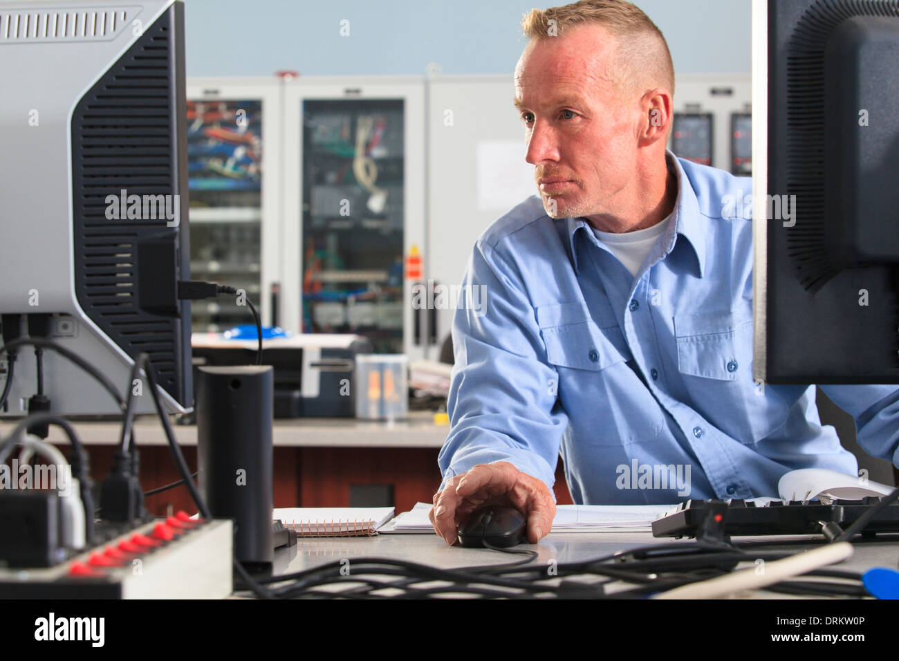 Electrical engineer using computer mouse while monitoring operations at ...