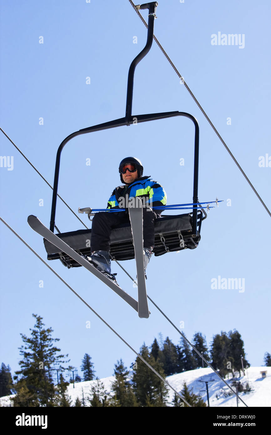 Man skier on chair lift going up the mountain Stock Photo - Alamy