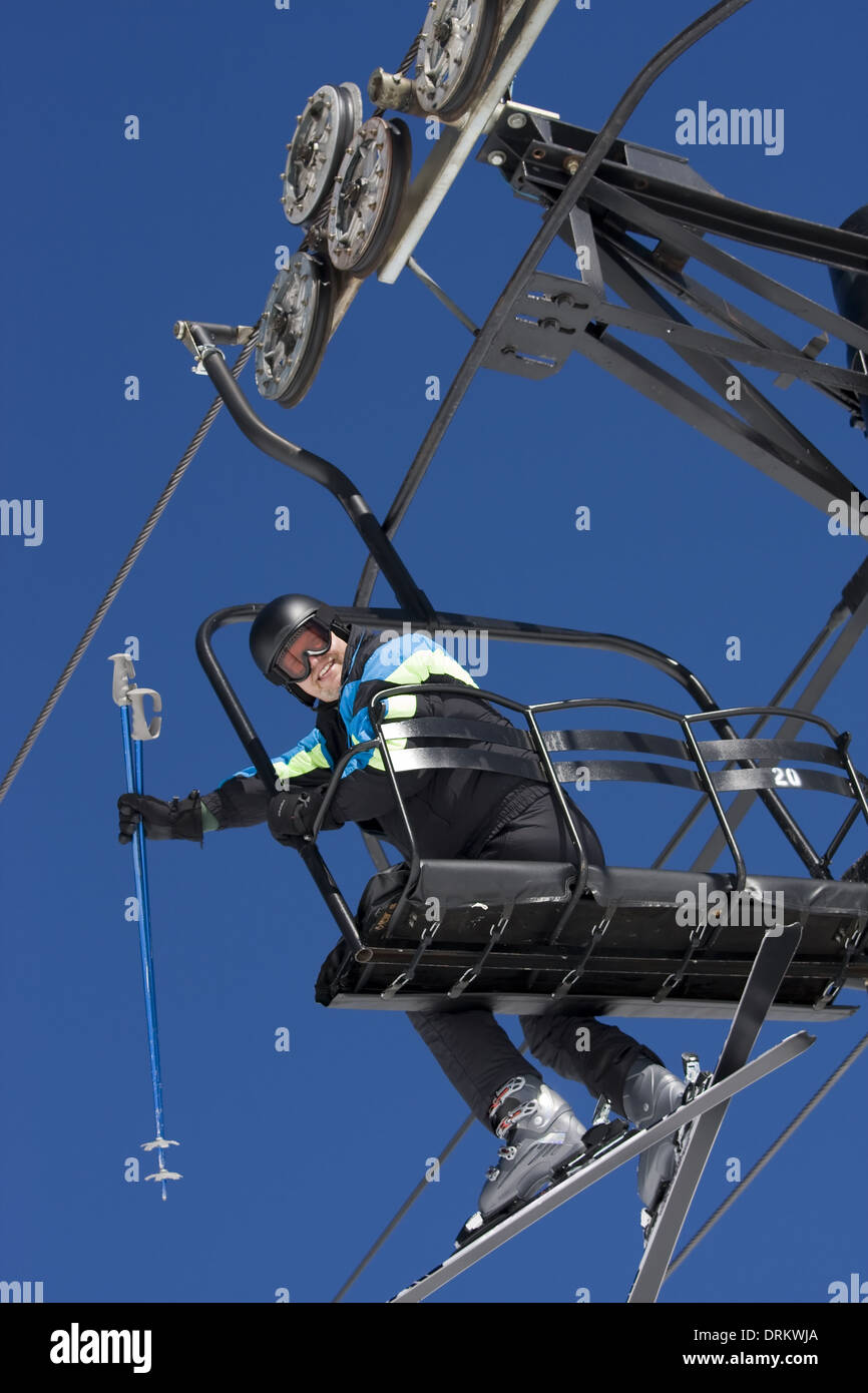 Man on ski lift looking behind holding out poles Stock Photo - Alamy
