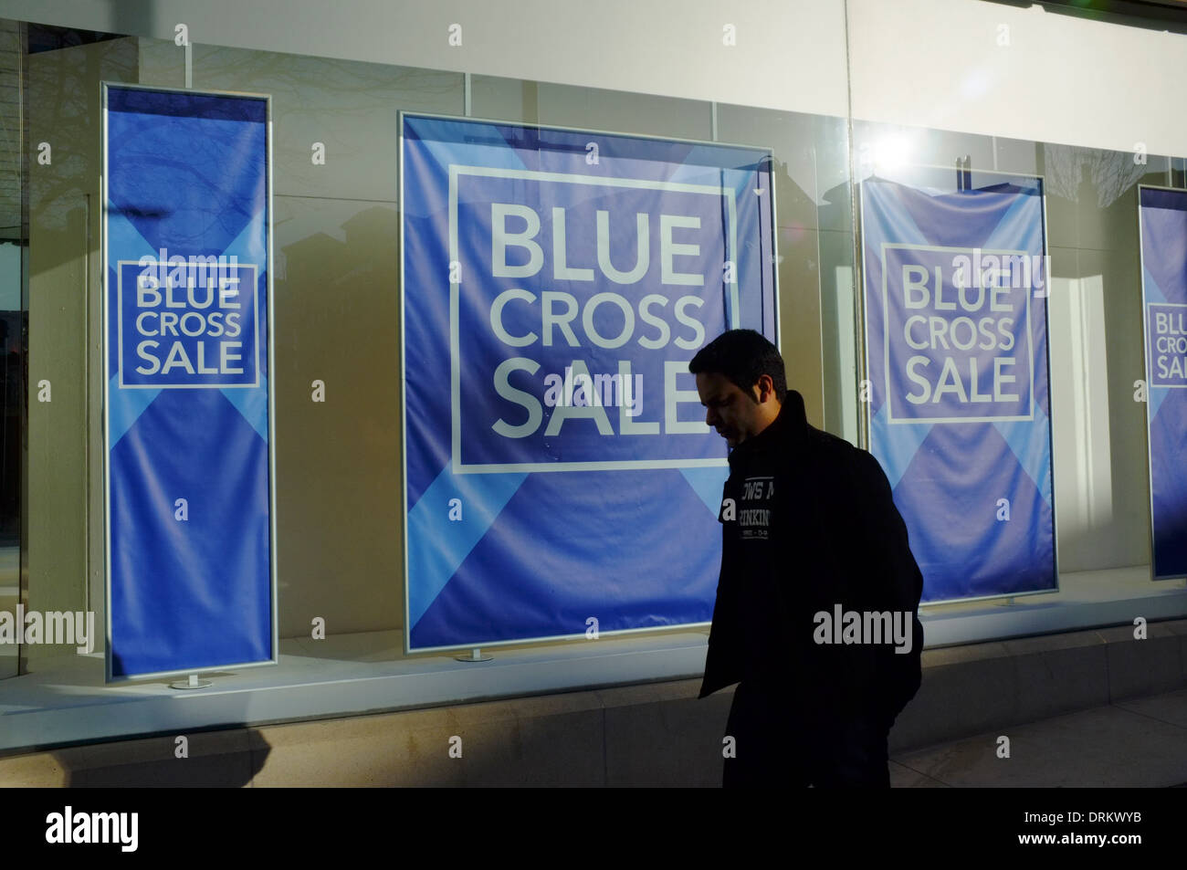 Man walking past Blue Cross Sale posters at DEBENHAMS department store ...