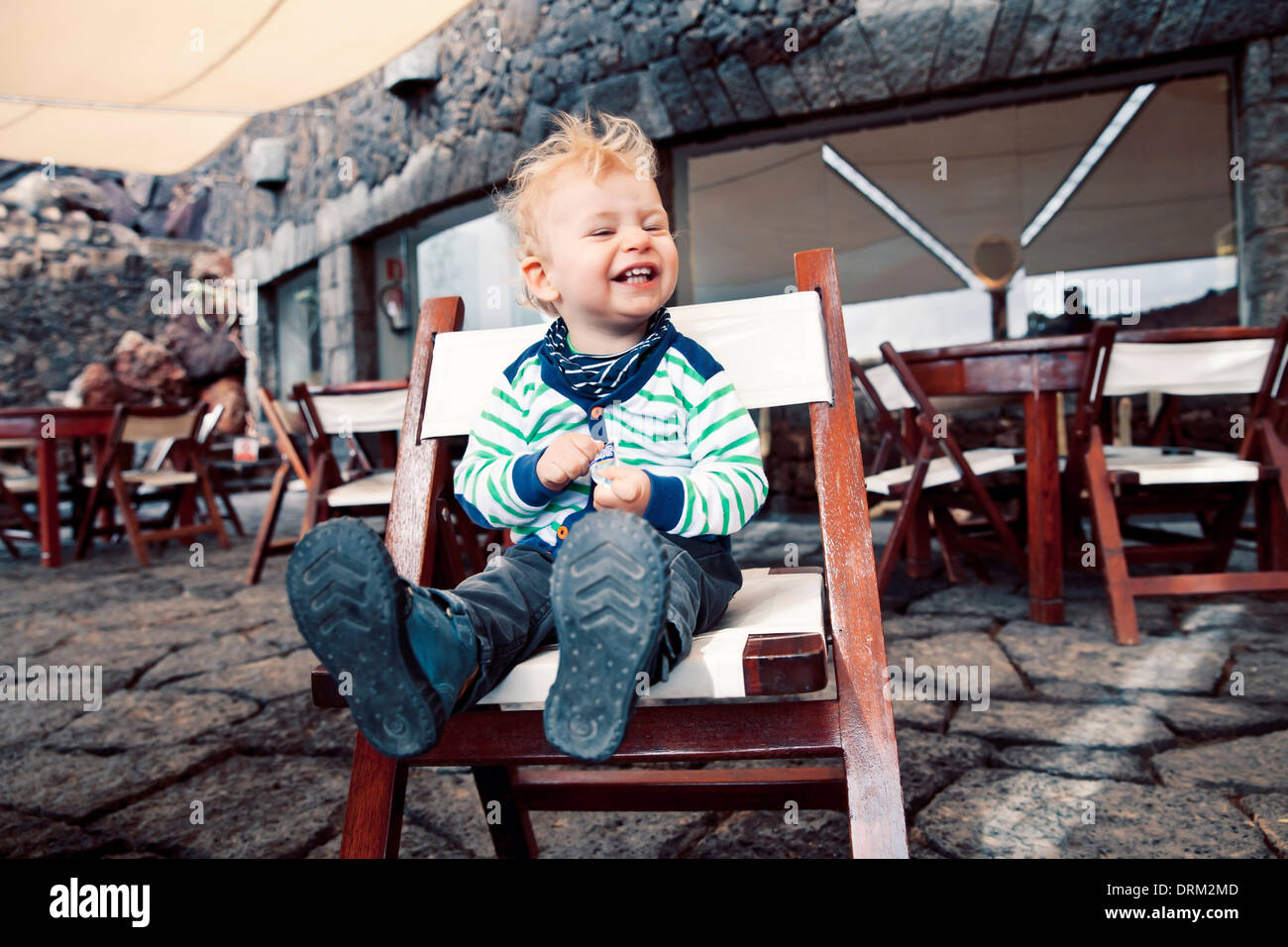 Spain, Lanzarote, laughing little boy sitting on a terrace of a ...