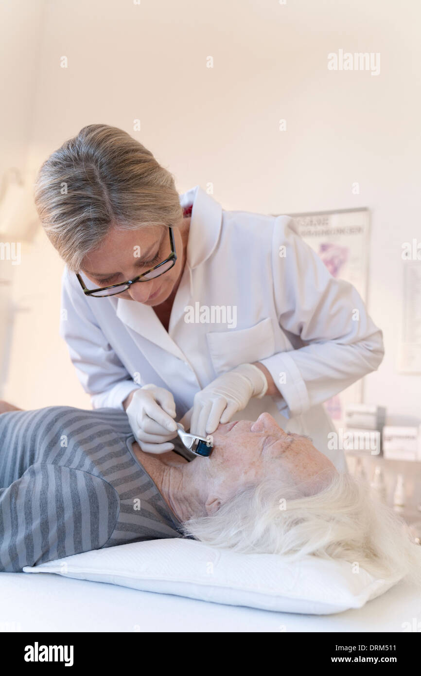 Female alternative practitioner treating senior woman with derm roller ...