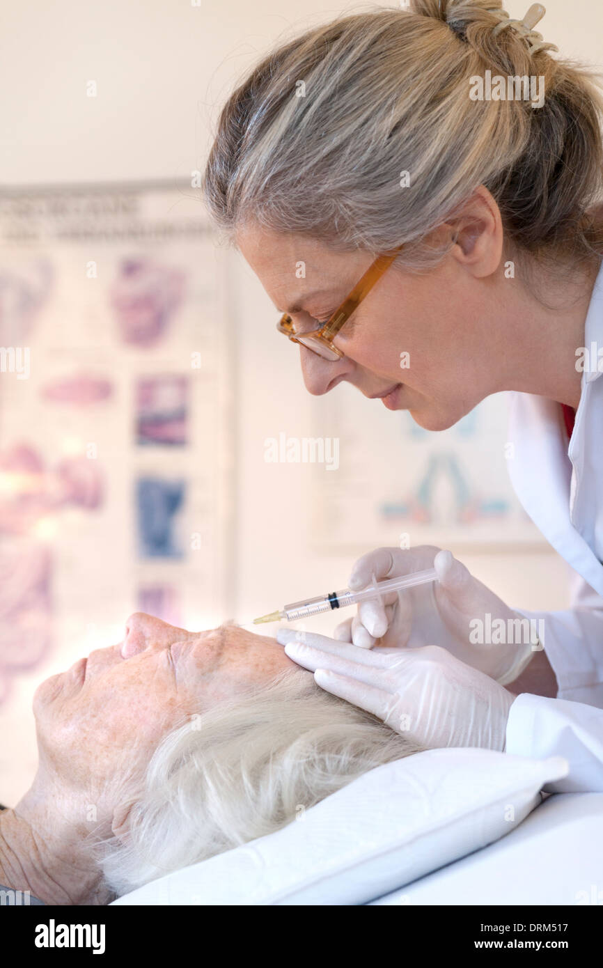 Female alternative practitioner giving senior woman injection ...